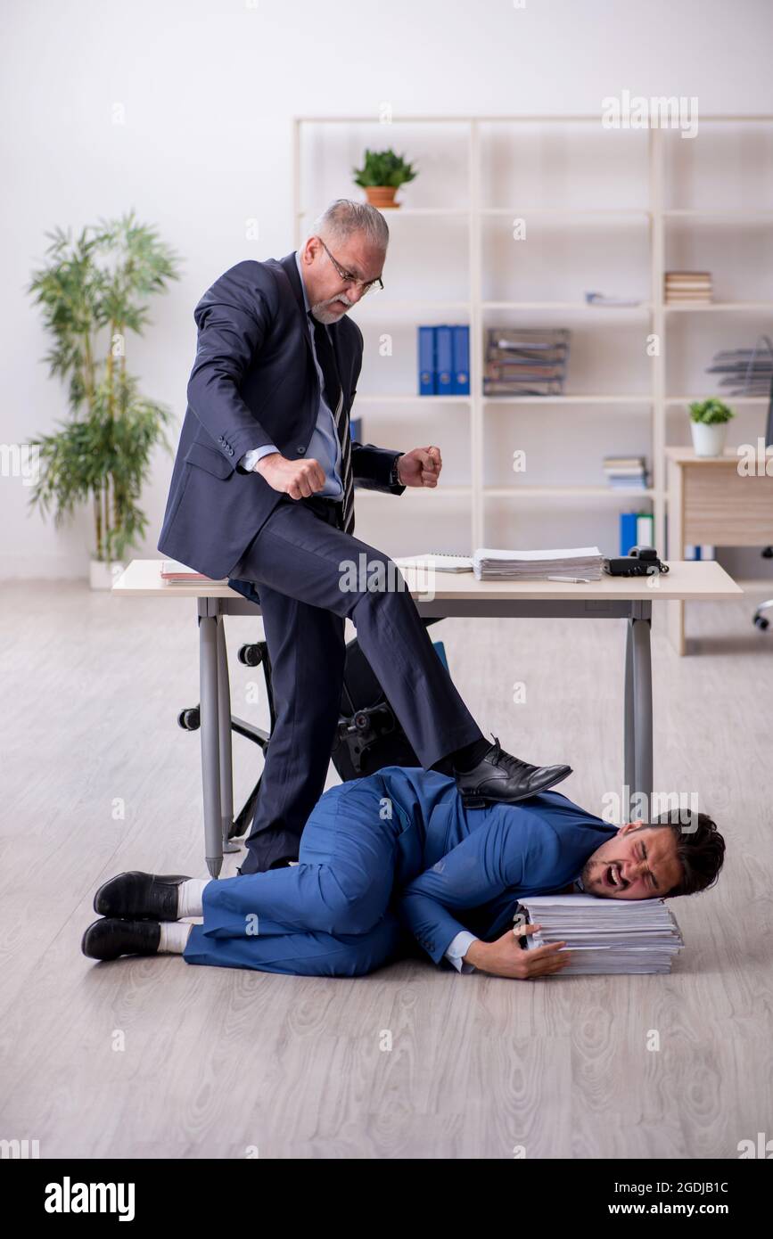 Old boss and young employee in bullying concept Stock Photo - Alamy