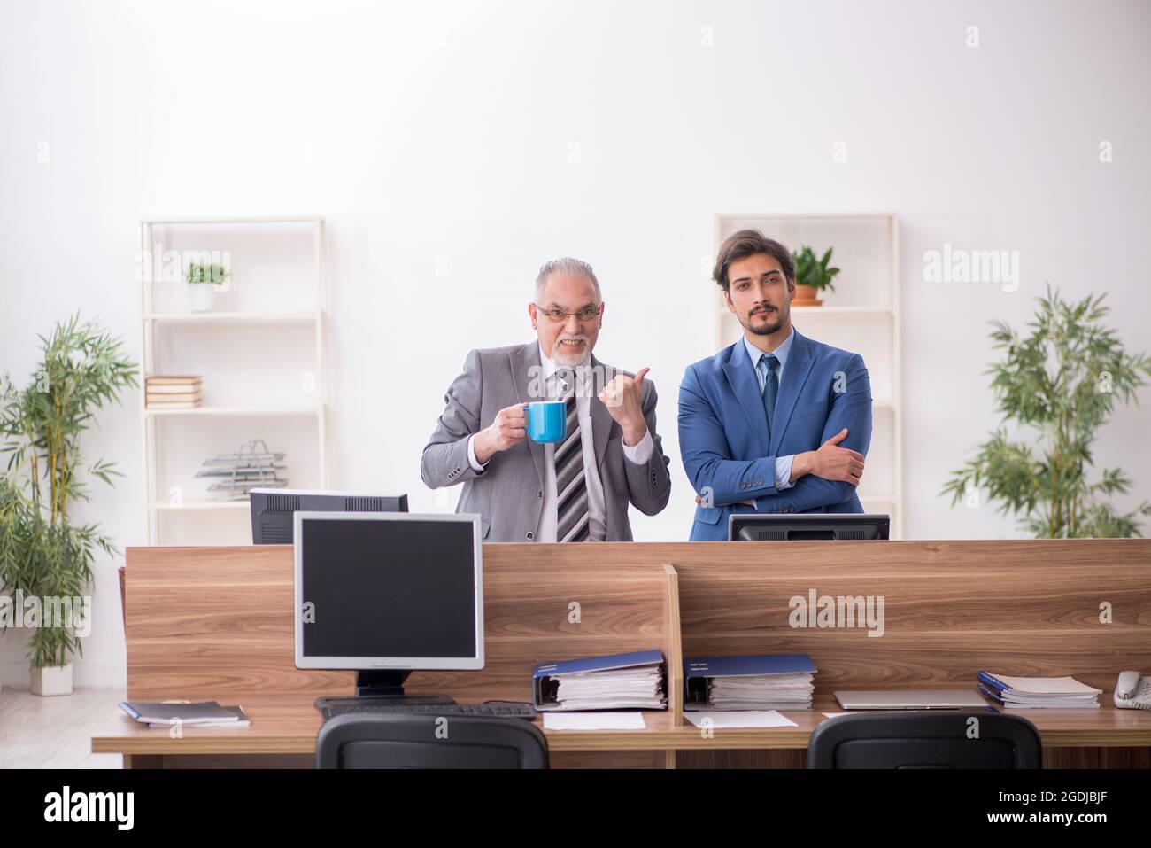 Two male employees working at workplace Stock Photo - Alamy