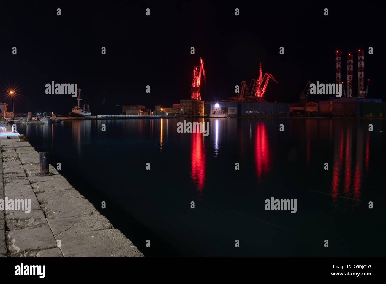 A night view of the harbor in Pula (Croatia) with colorfully lit cranes ...