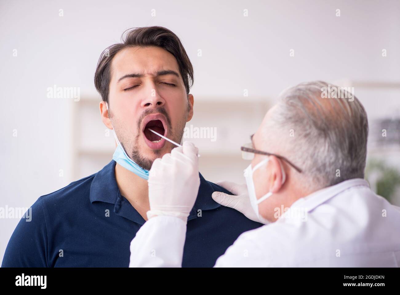 Young patient visiting old male doctor during pandemic Stock Photo - Alamy