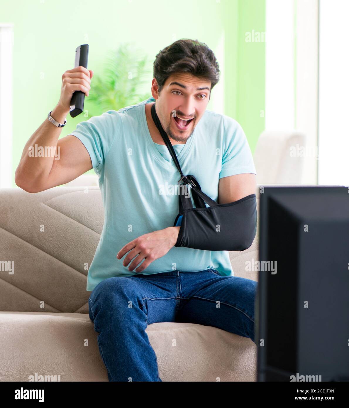 The arm injured man sitting on the sofa watching tv Stock Photo - Alamy