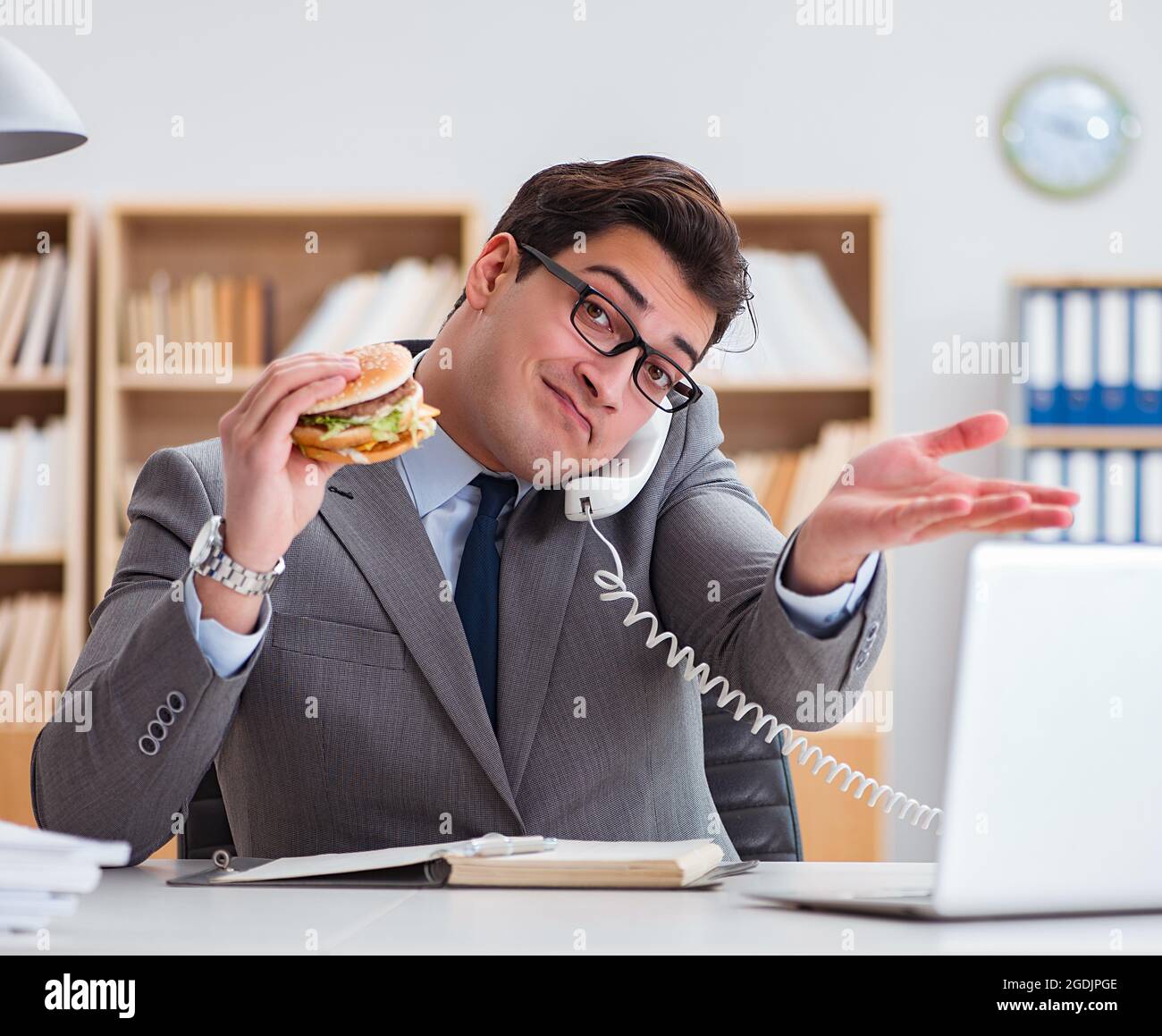 The hungry funny businessman eating junk food sandwich Stock Photo - Alamy