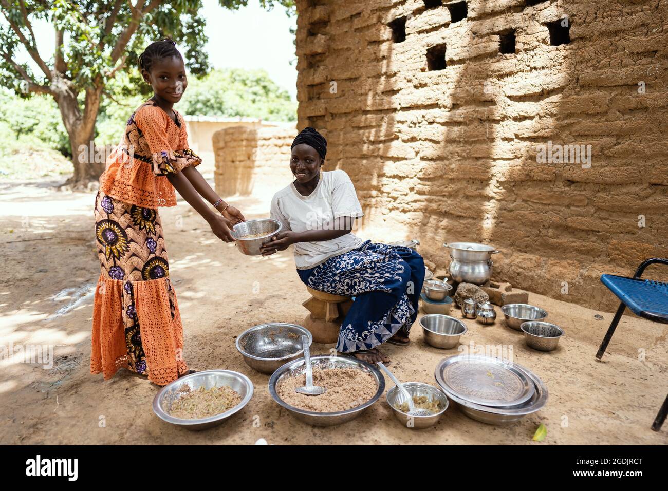 Black African cook sitting on a small wooden chair in the middle of ...