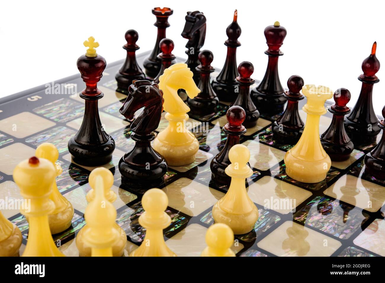 Natural amber different chess pieces figures standing on pearl board in ...