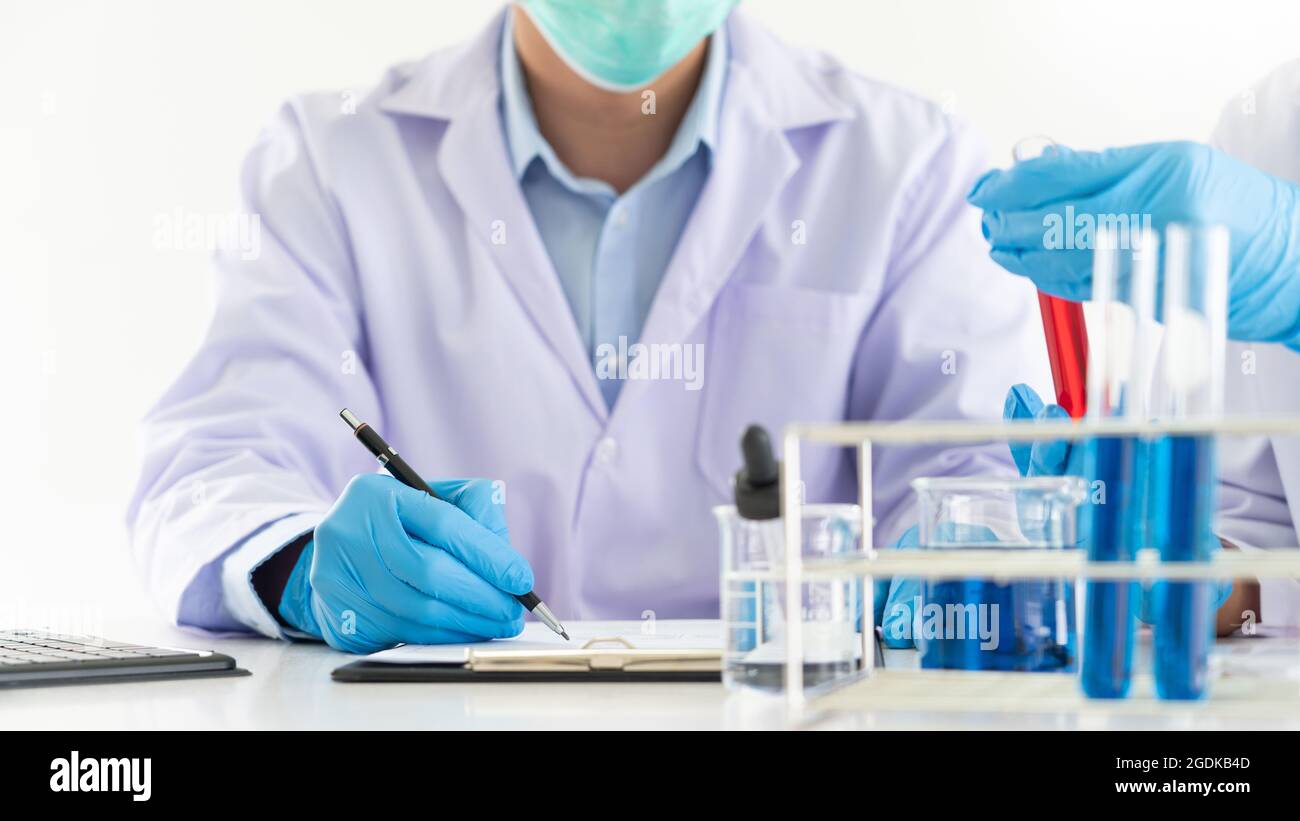 Attractive young scientist team in lab coat and safety goggles working ...