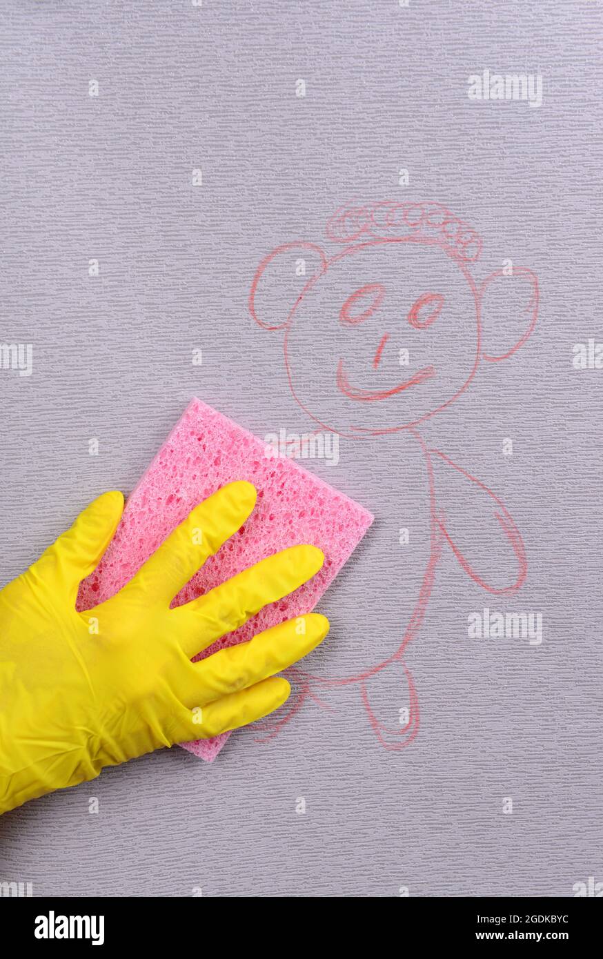 Hand in glove wiping children drawing on wallpaper Stock Photo - Alamy