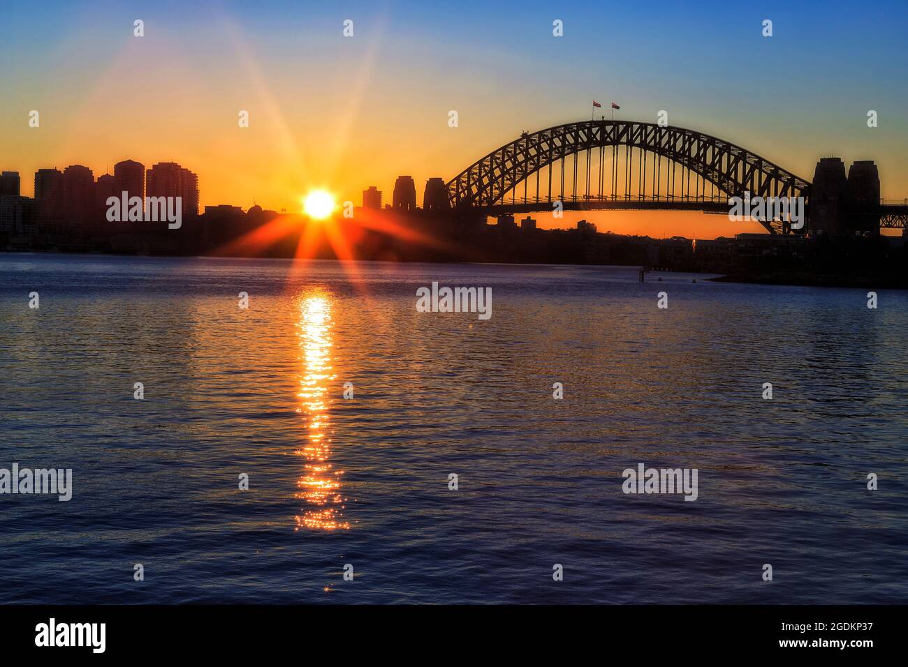 Rising sun crossing the Sydney Harbour bridge across Harbour waters in ...