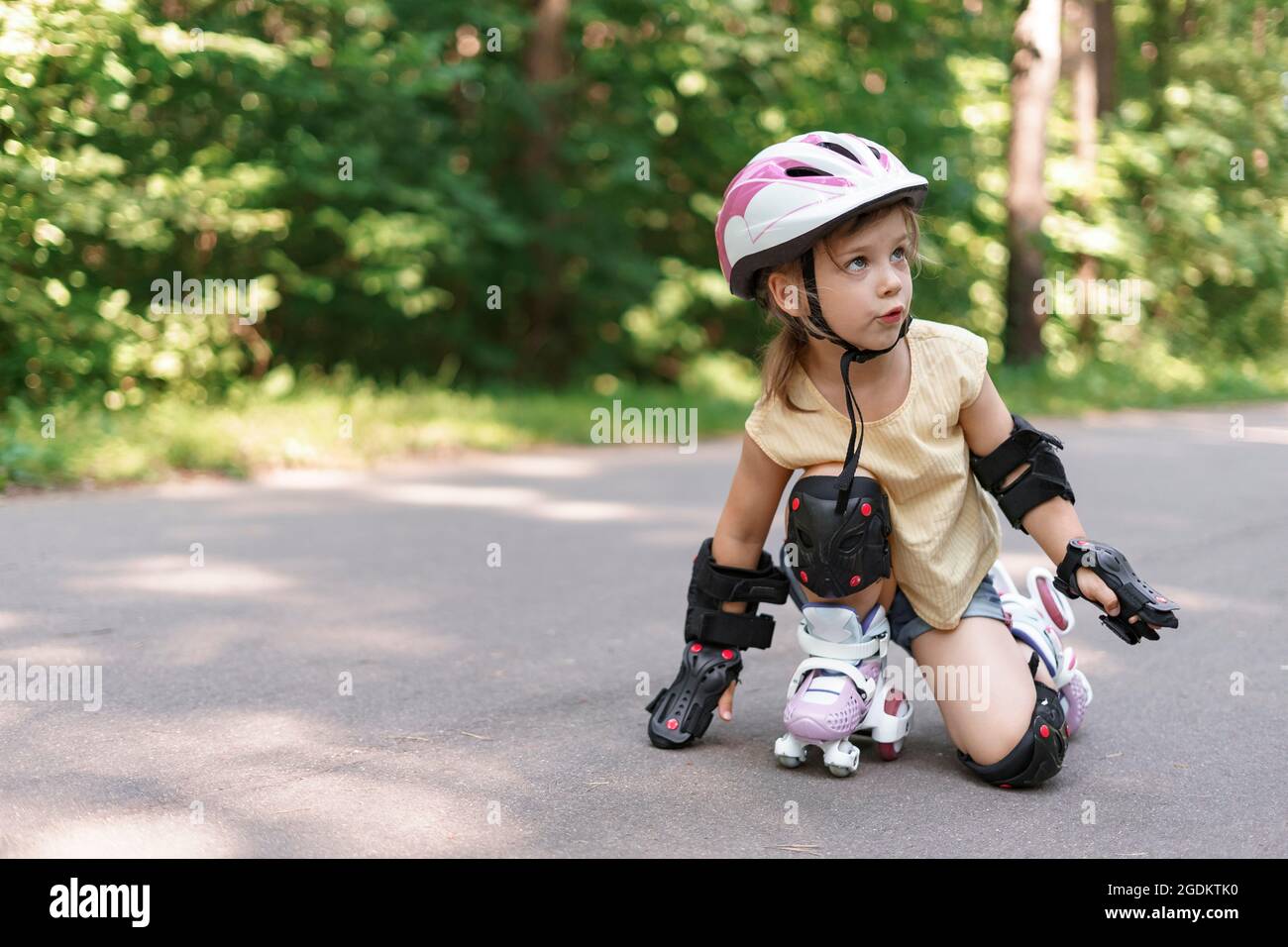 baby in protective sportswear. little girl learning to roller skate ...