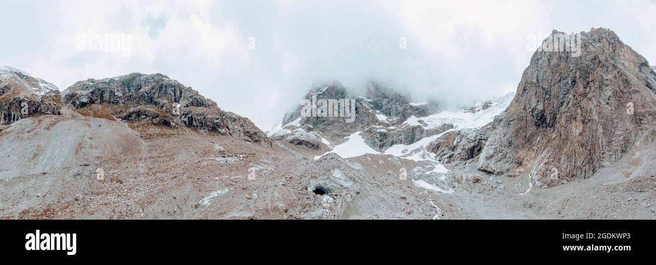 drone view over a desolate receding alpine glacier surrounded by ...