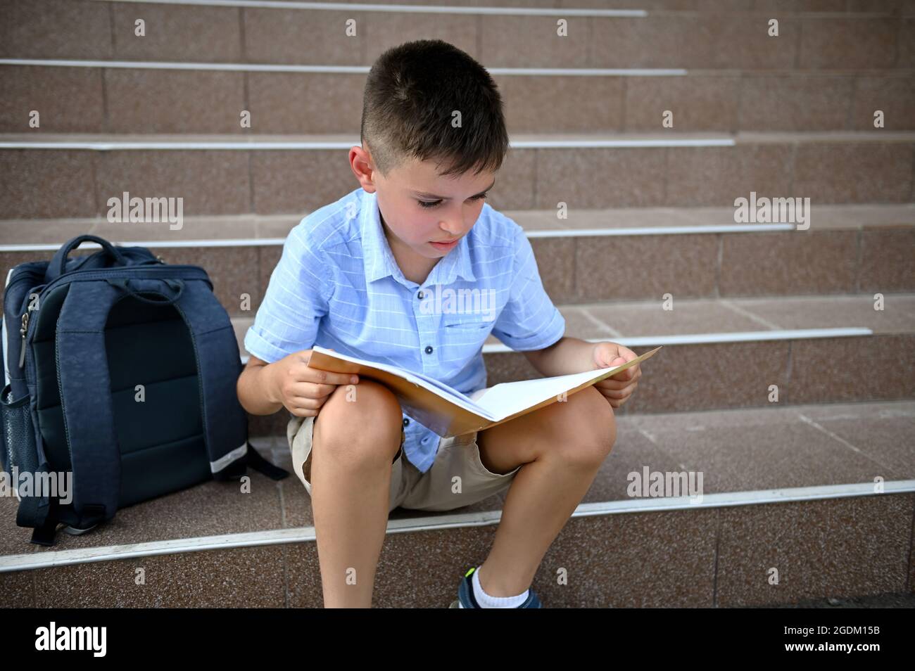 Puzzled elementary school student, pupil, school boy, doing his ...