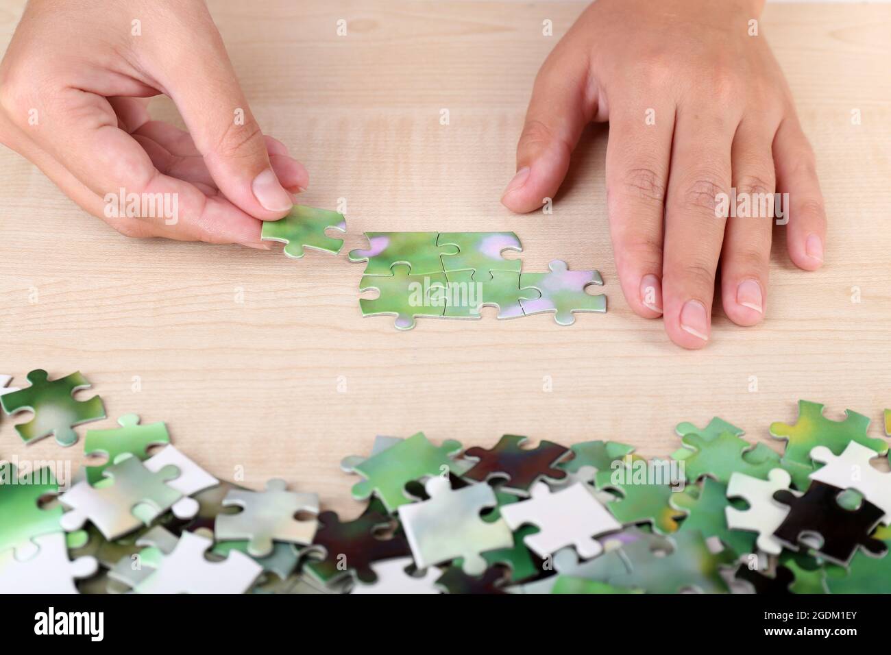 Hand holding puzzle piece on wooden table background Stock Photo - Alamy