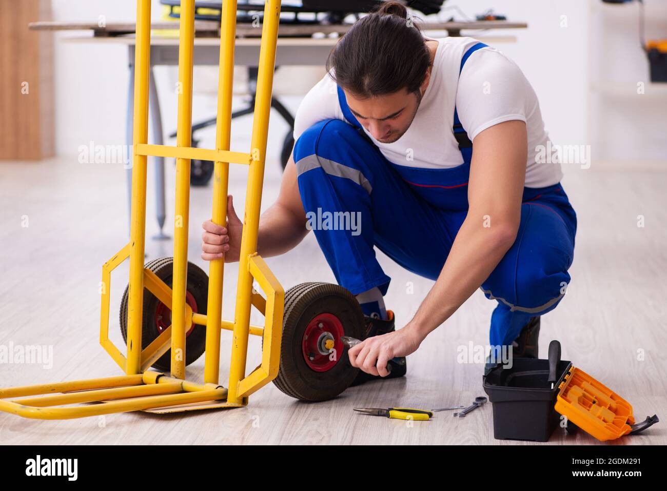 Young repairman repairing trolley indoors Stock Photo - Alamy