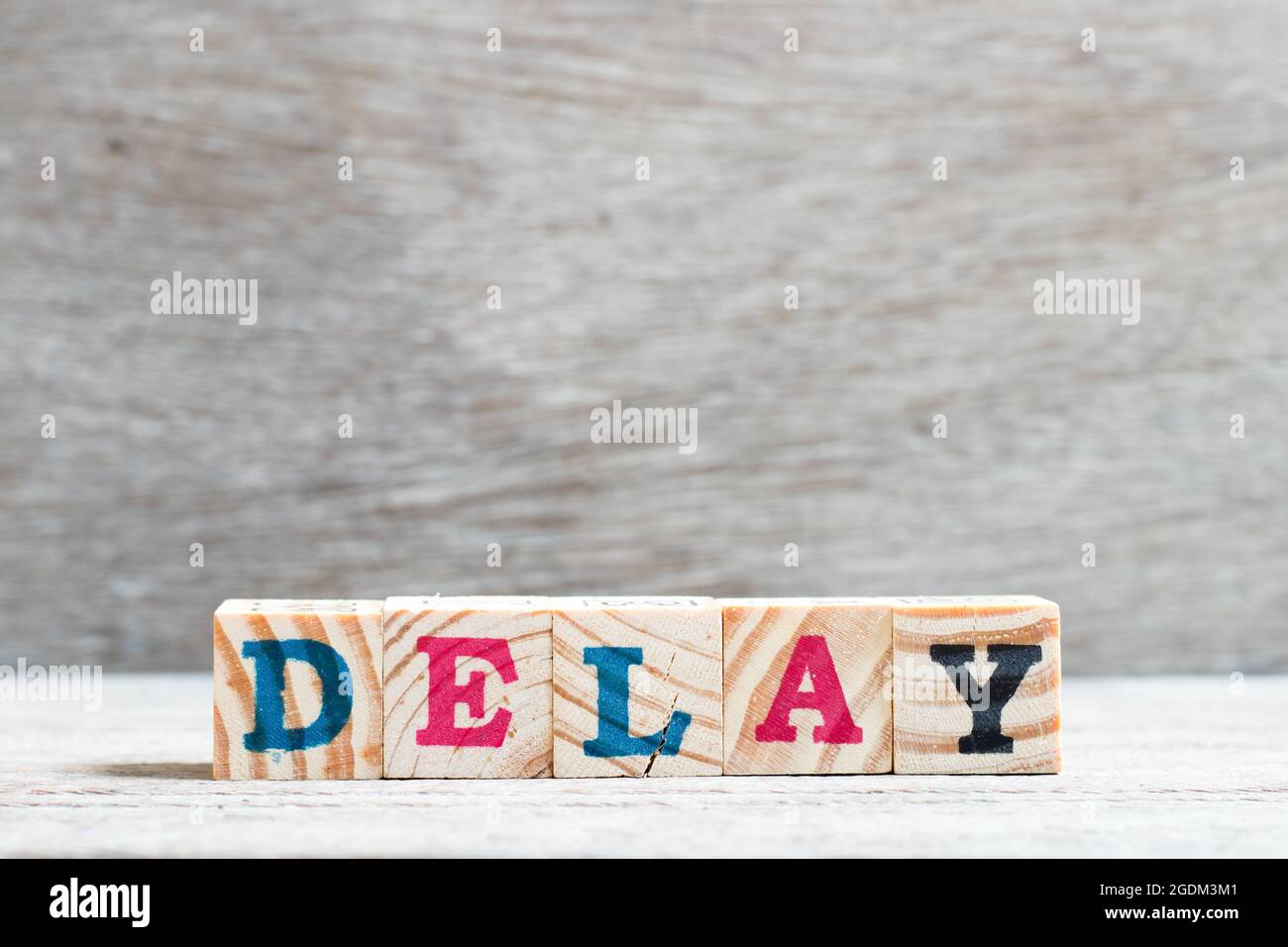 Letter block in word delay on wood background Stock Photo - Alamy