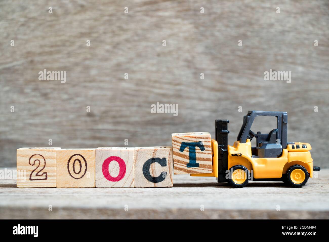 Toy forklift hold block T to complete word 20 oct on wood background ...