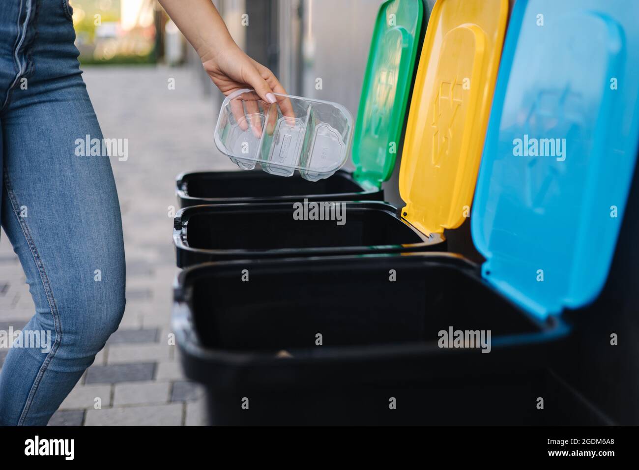Close-up of female throwing plastic container in recycling bin ...