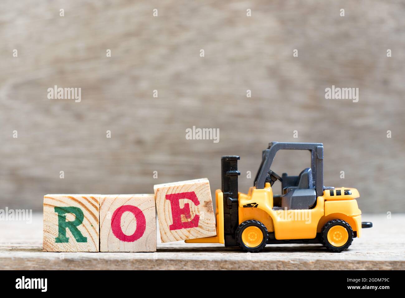 Toy forklift hold letter block in word ROE (abbreviation of return on ...