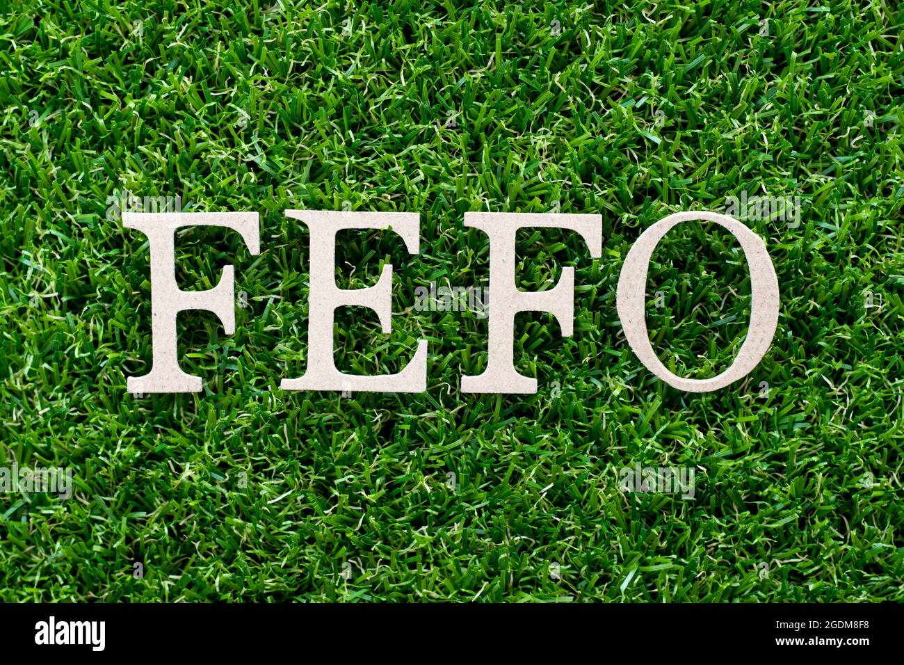 Wood letter in word FEFO (first expired first out) on artificial green ...