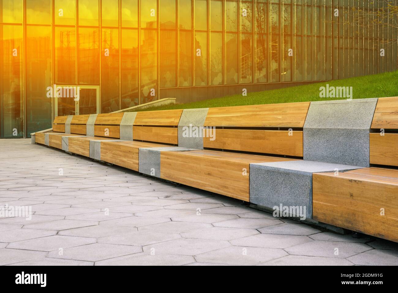 Wooden bench and tiled walkway. Office building for the work of company ...
