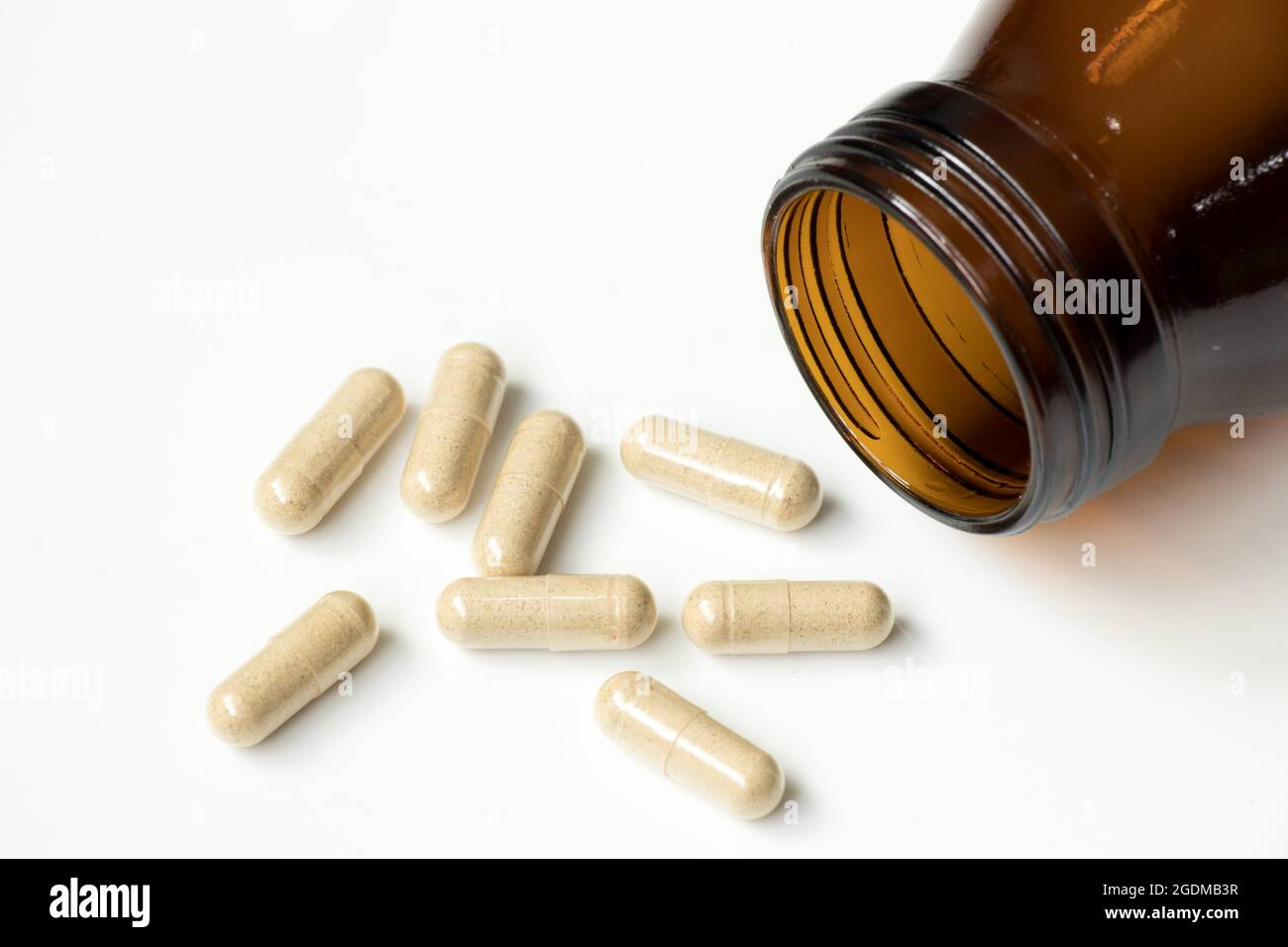 Transparent hard capsule with brown powder and amber glass bottle on ...