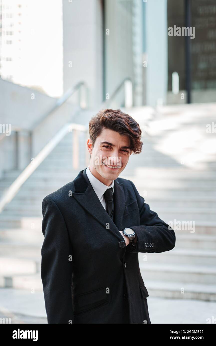 Vertical shot of a cheerful young Caucasian guy wearing a suit taking ...