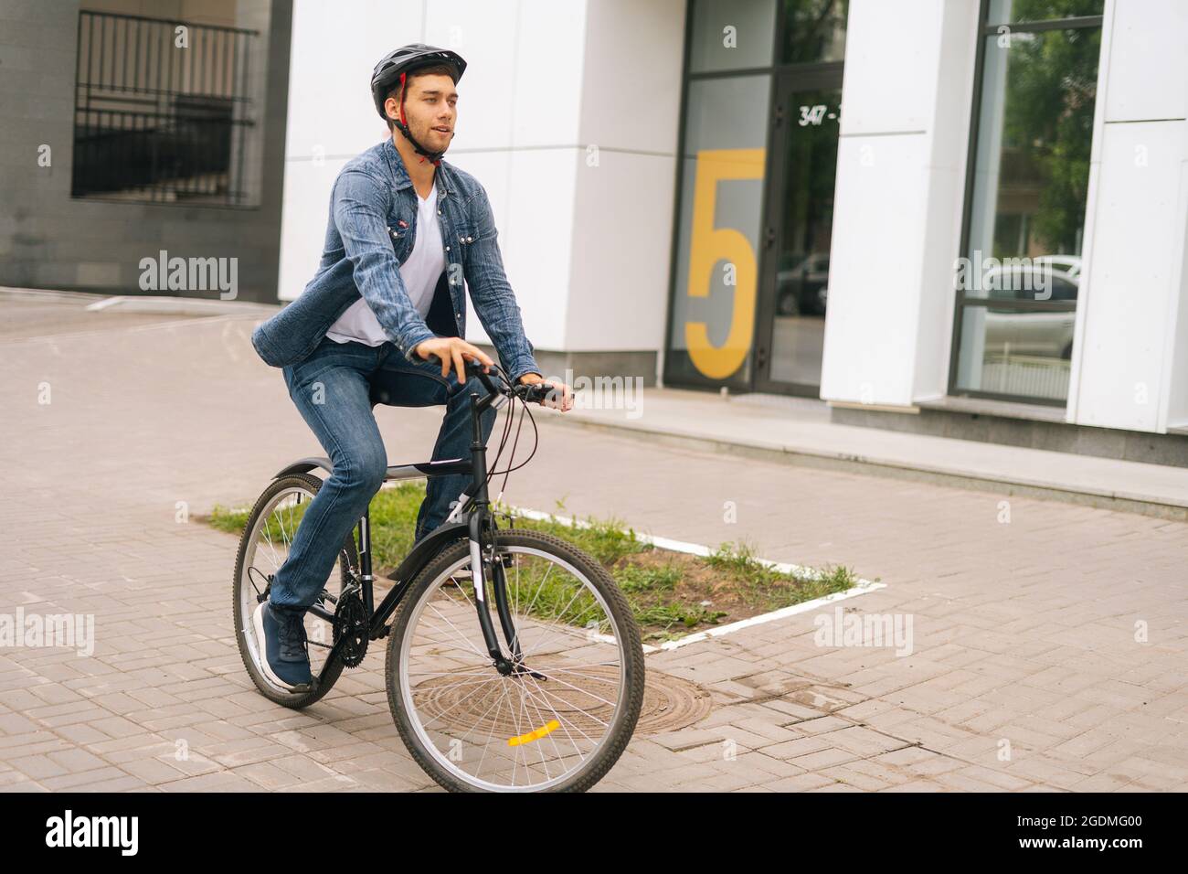 Caucasian handsome young man in protective helmet goes out for bicycle ...