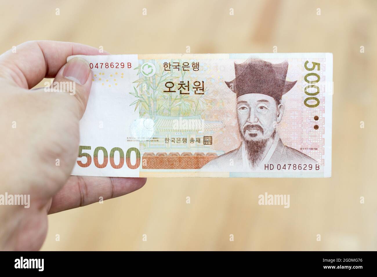 Business man hold south korea banknote 5000 korean won on wood ...