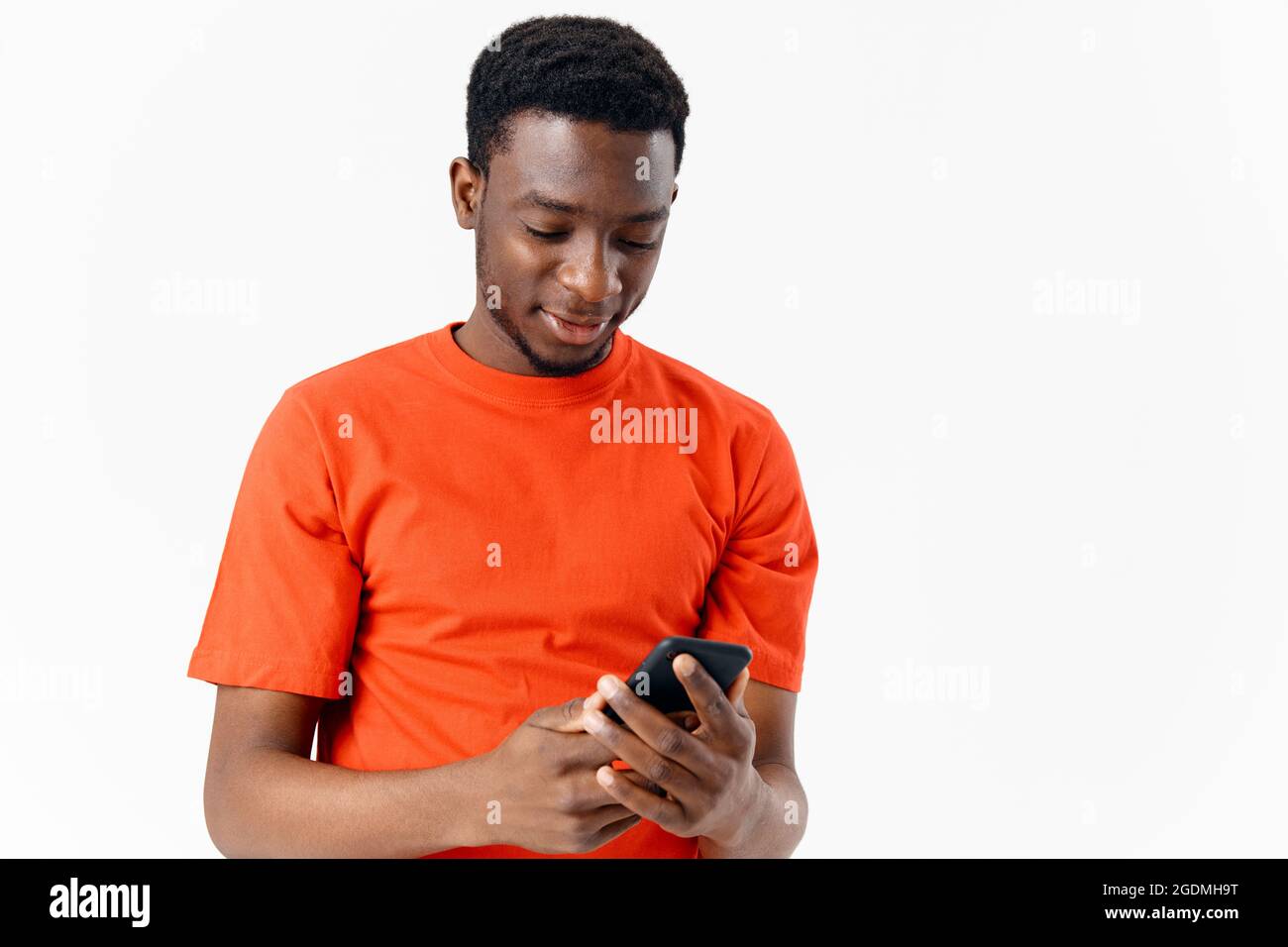 a guy in an orange t-shirt looks at the screen of a mobile phone on a ...