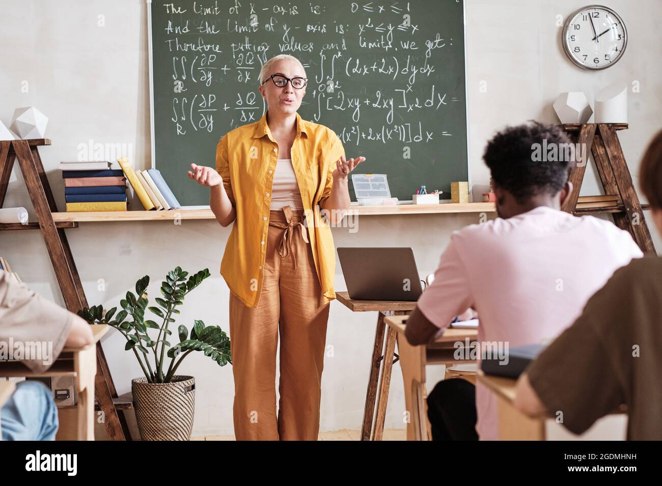 Teacher standing at the blackboard and gesturing she explaining new ...