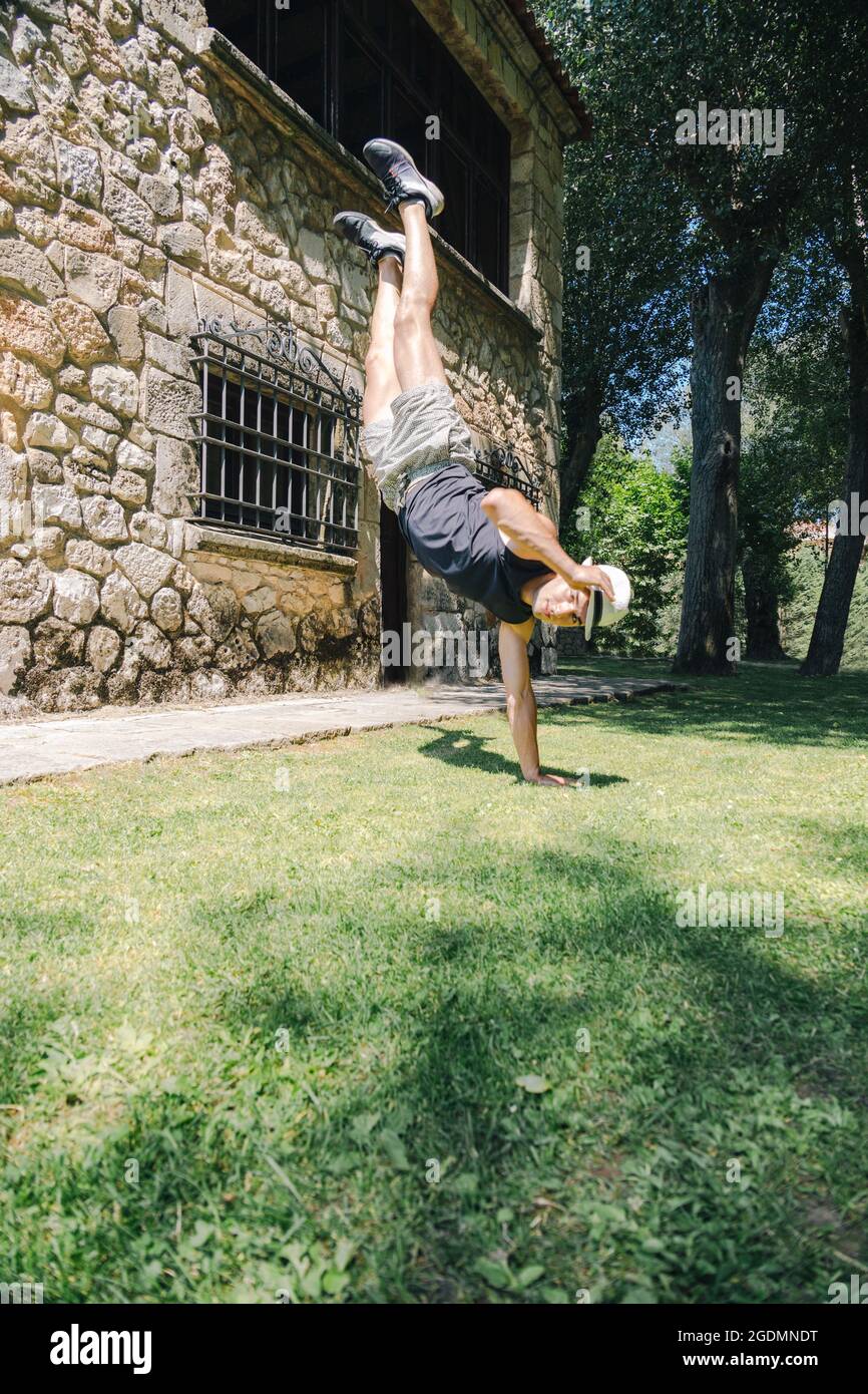 young caucasian boy performing a handstand in a funny way with a cap in ...