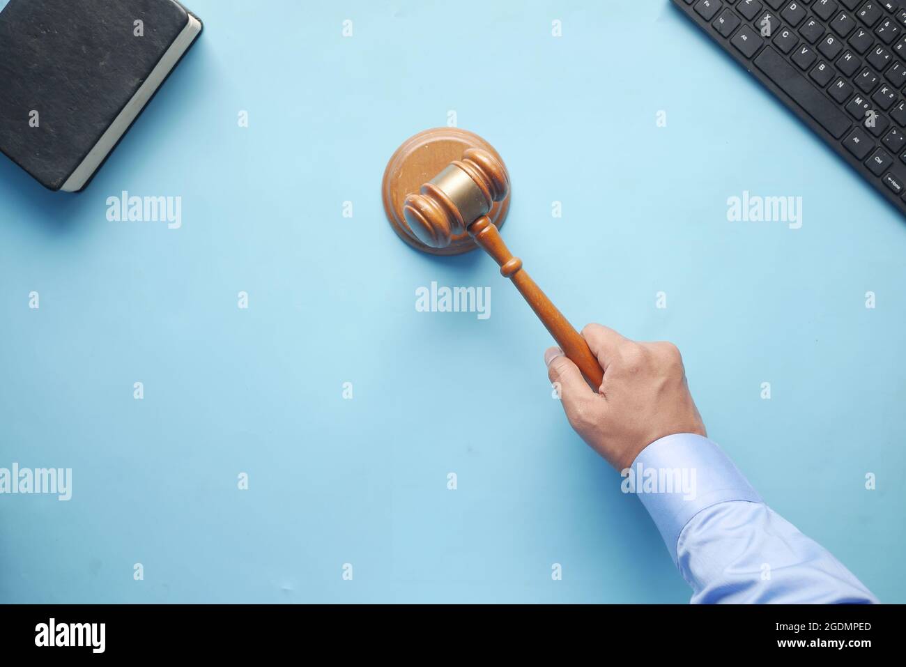 top view of person's hand striking the gavel on blue background Stock ...