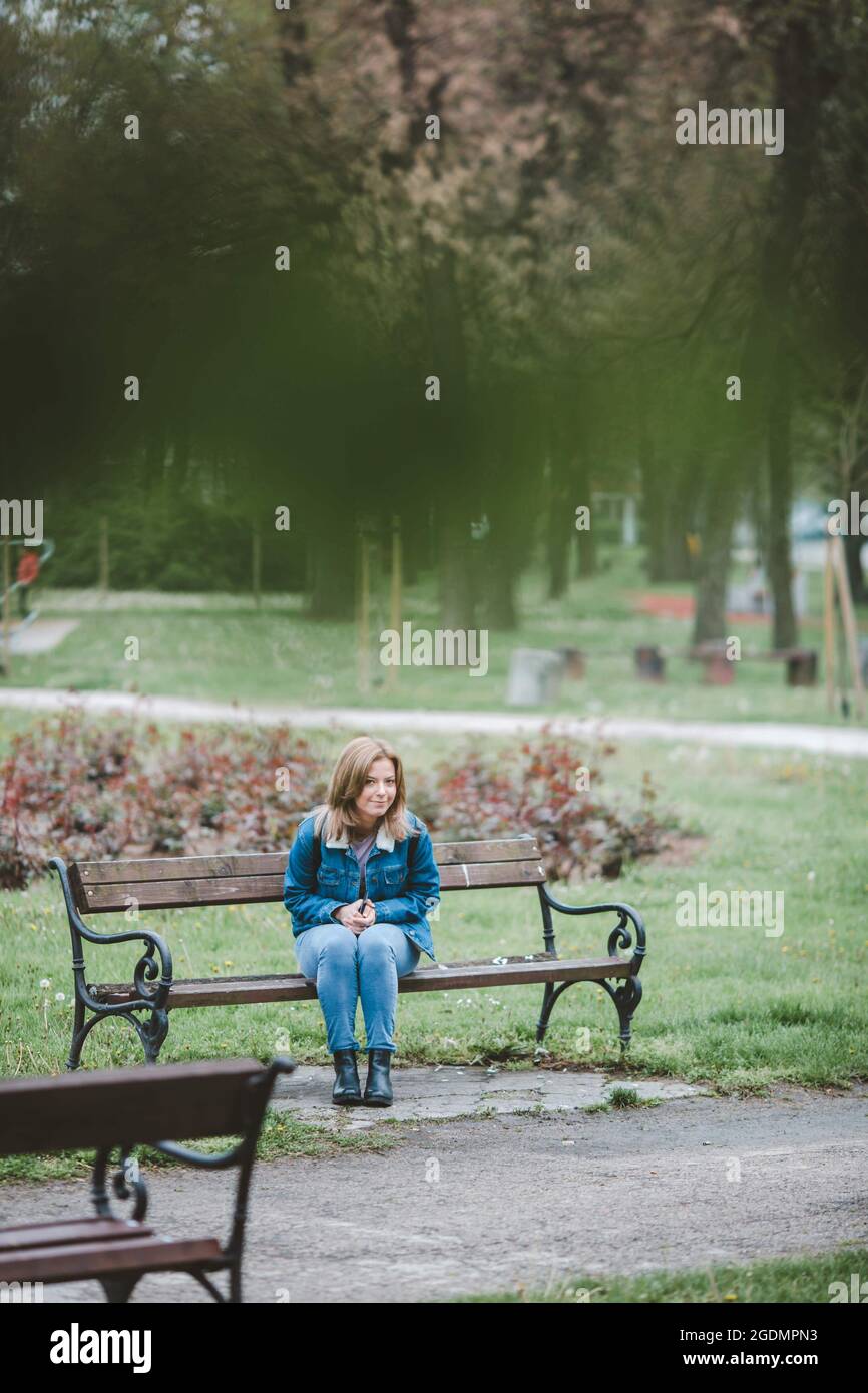 Shallow focus vertical shot of a young blonde woman sitting on a wooden ...