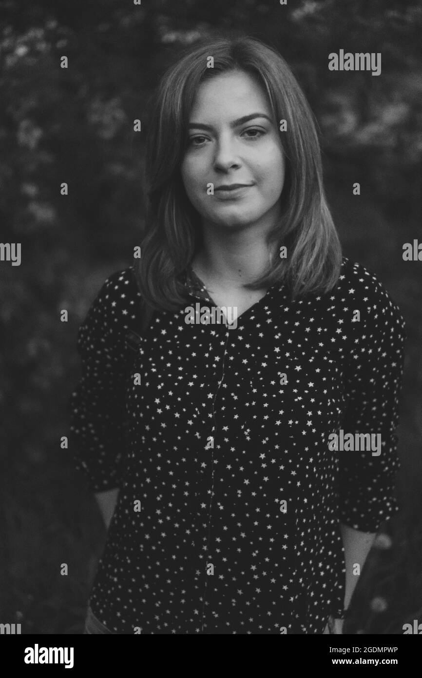 Shallow focus grayscale shot of a young woman posing in front of the ...