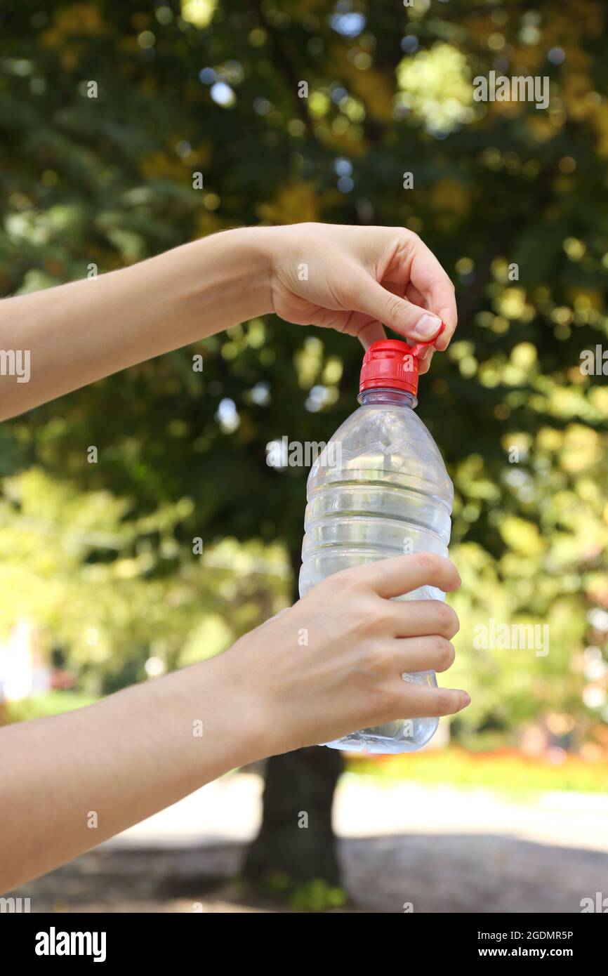 Hand opening bottle with water on bright background Stock Photo - Alamy