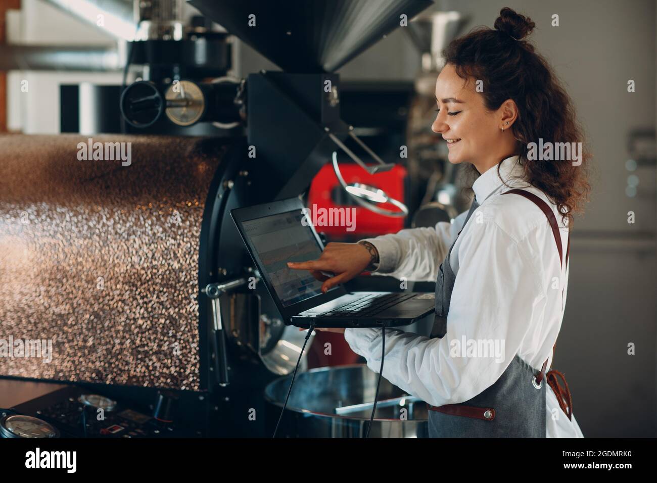 Coffee roaster machine and barista woman with laptop computer at coffee ...