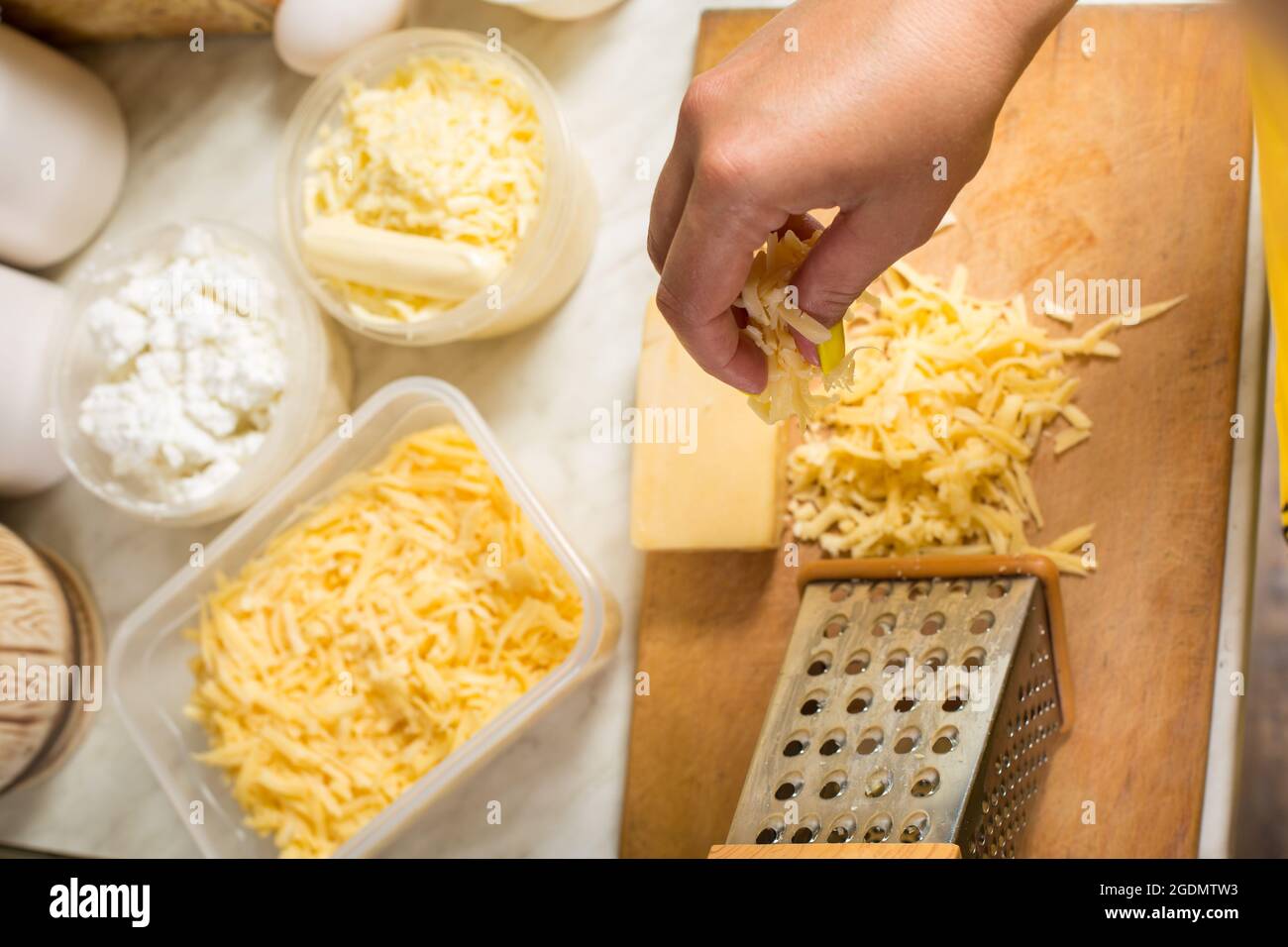 Parmesan cheese shredded on steel grater and female hands showing it ...