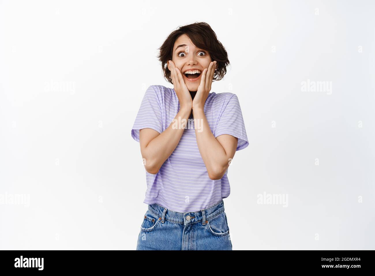 Surprised and excited brunette girl, smiling amazed, excited, receive ...