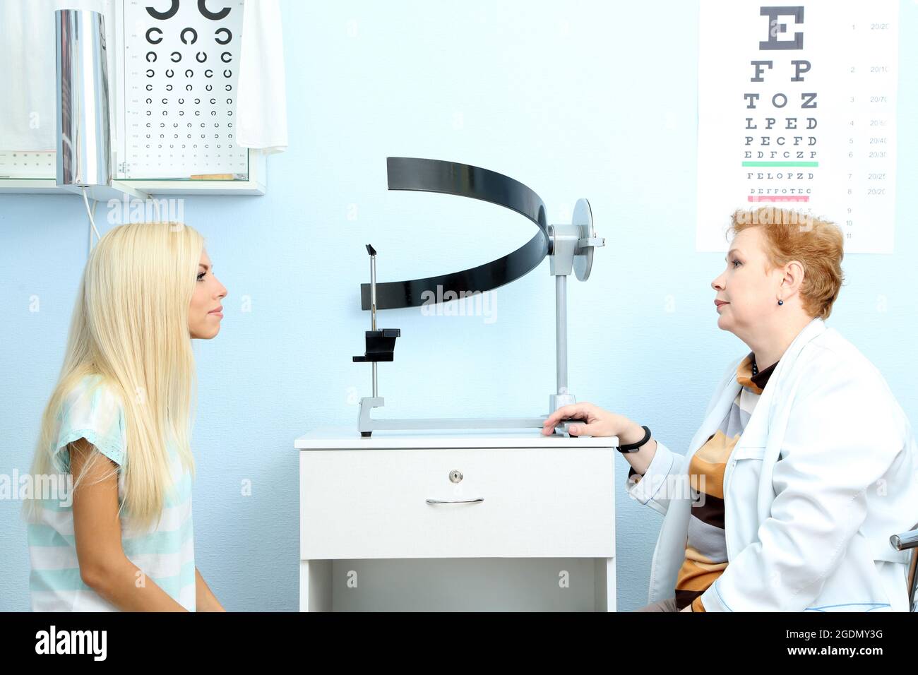 Optometry concept - pretty young woman having her eyes examined by eye ...