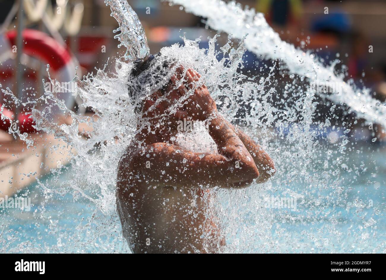 Sigmaringen, Germany. 14th Aug, 2021. A man cools off under a fountain ...