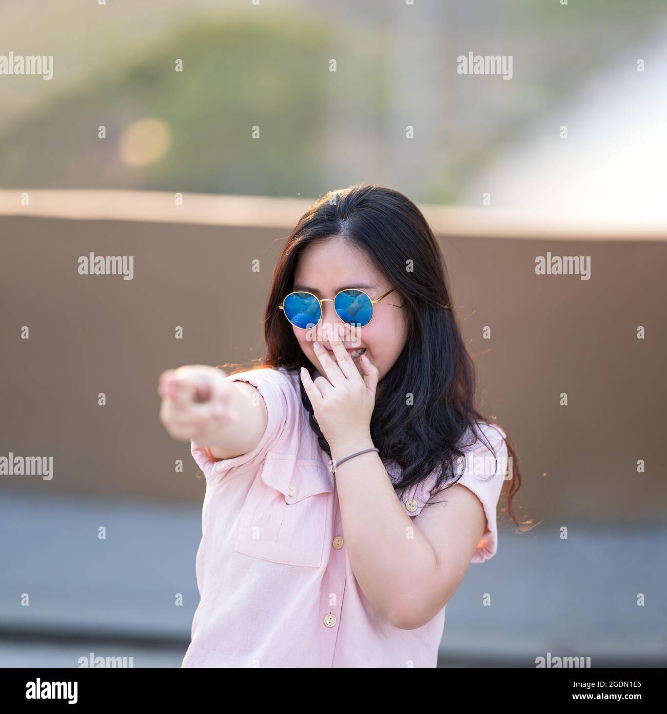 Asian woman in the pink shirt is playing finger gun, aim and focus on ...