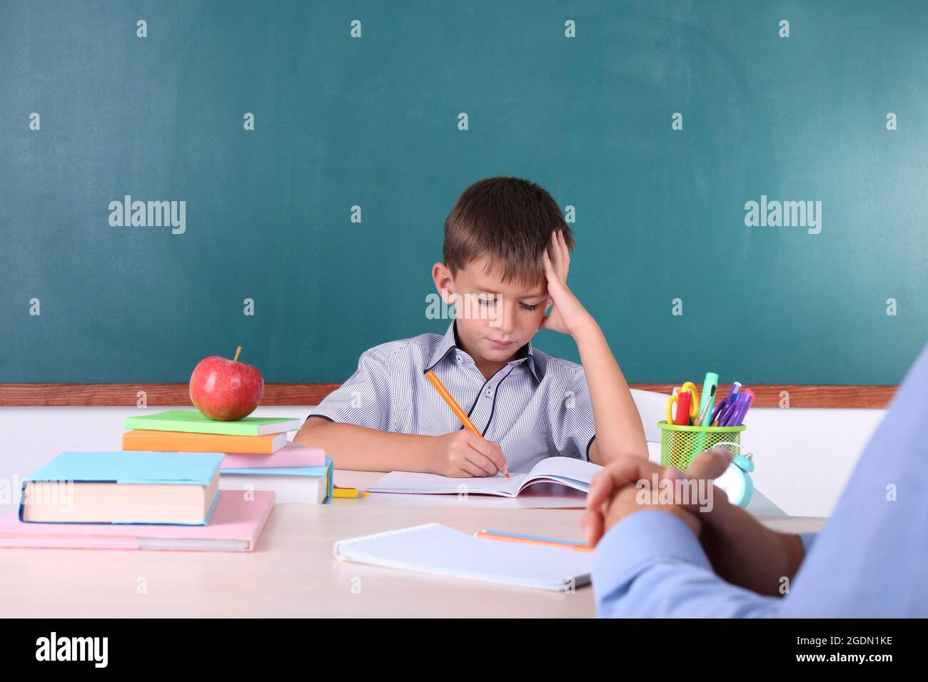 Schoolboy and teacher sitting in classroom on blackboard background ...