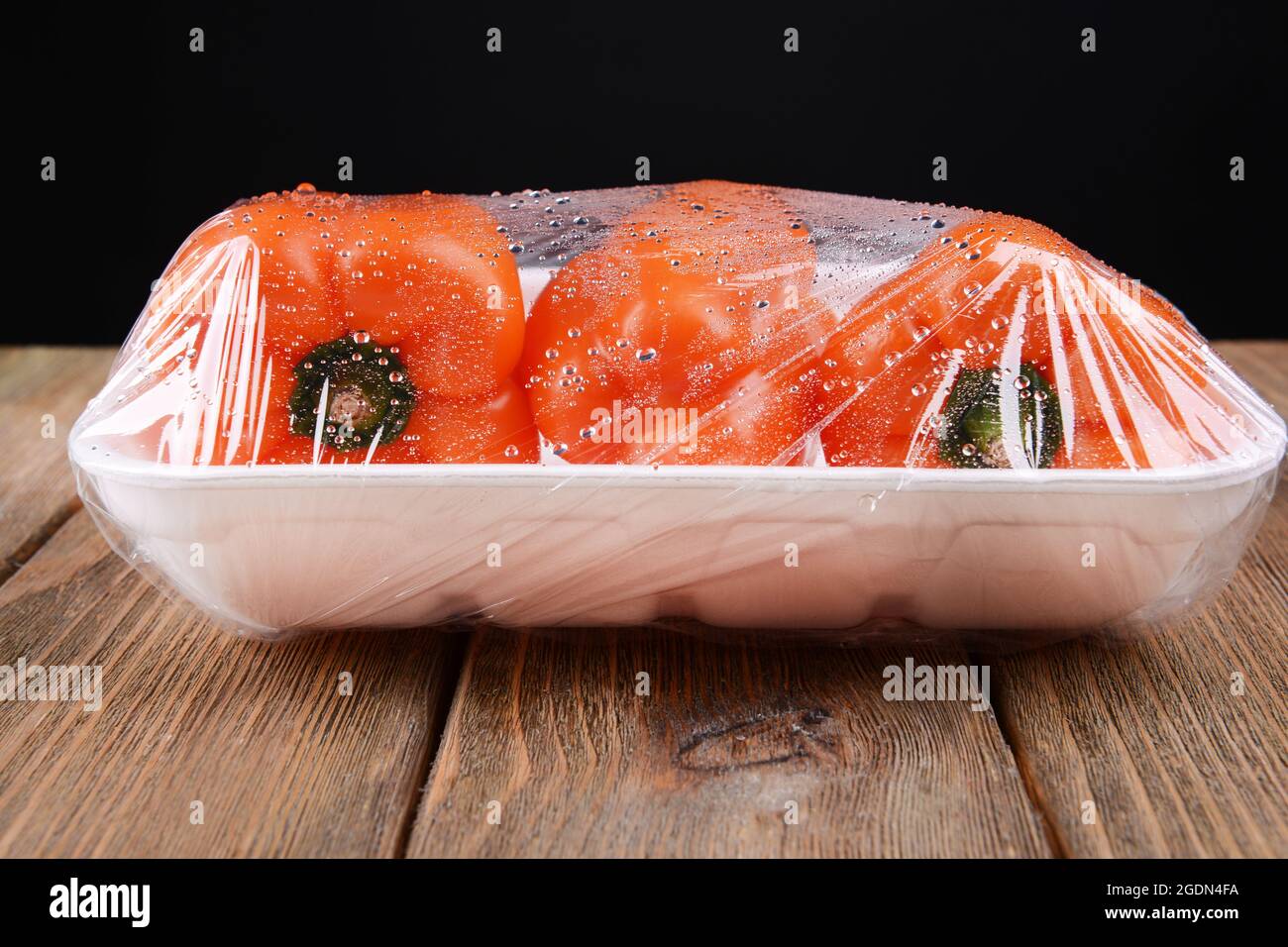 Pepper packed in food film on table on black background Stock Photo - Alamy