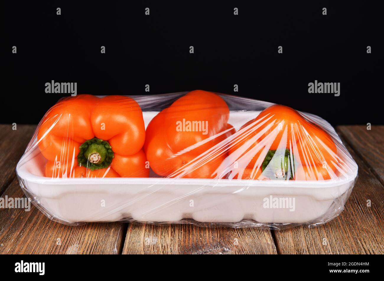 Pepper packed in food film on table on black background Stock Photo - Alamy