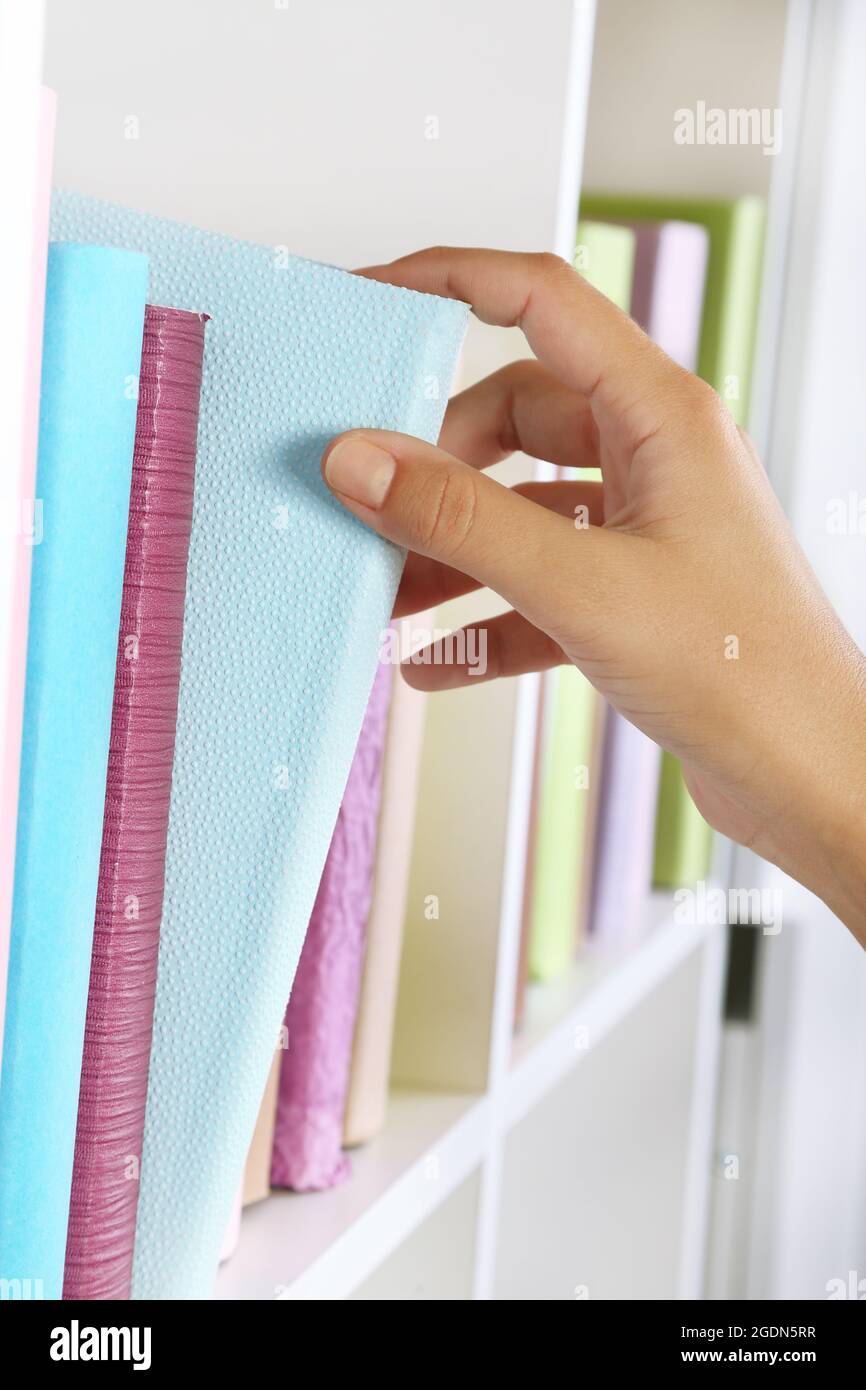 Hand picking book in library Stock Photo - Alamy