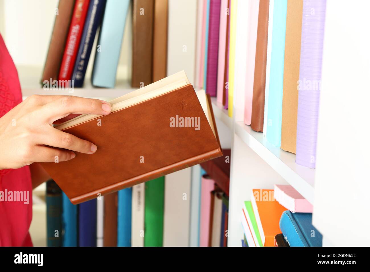 Hand picking book in library Stock Photo - Alamy
