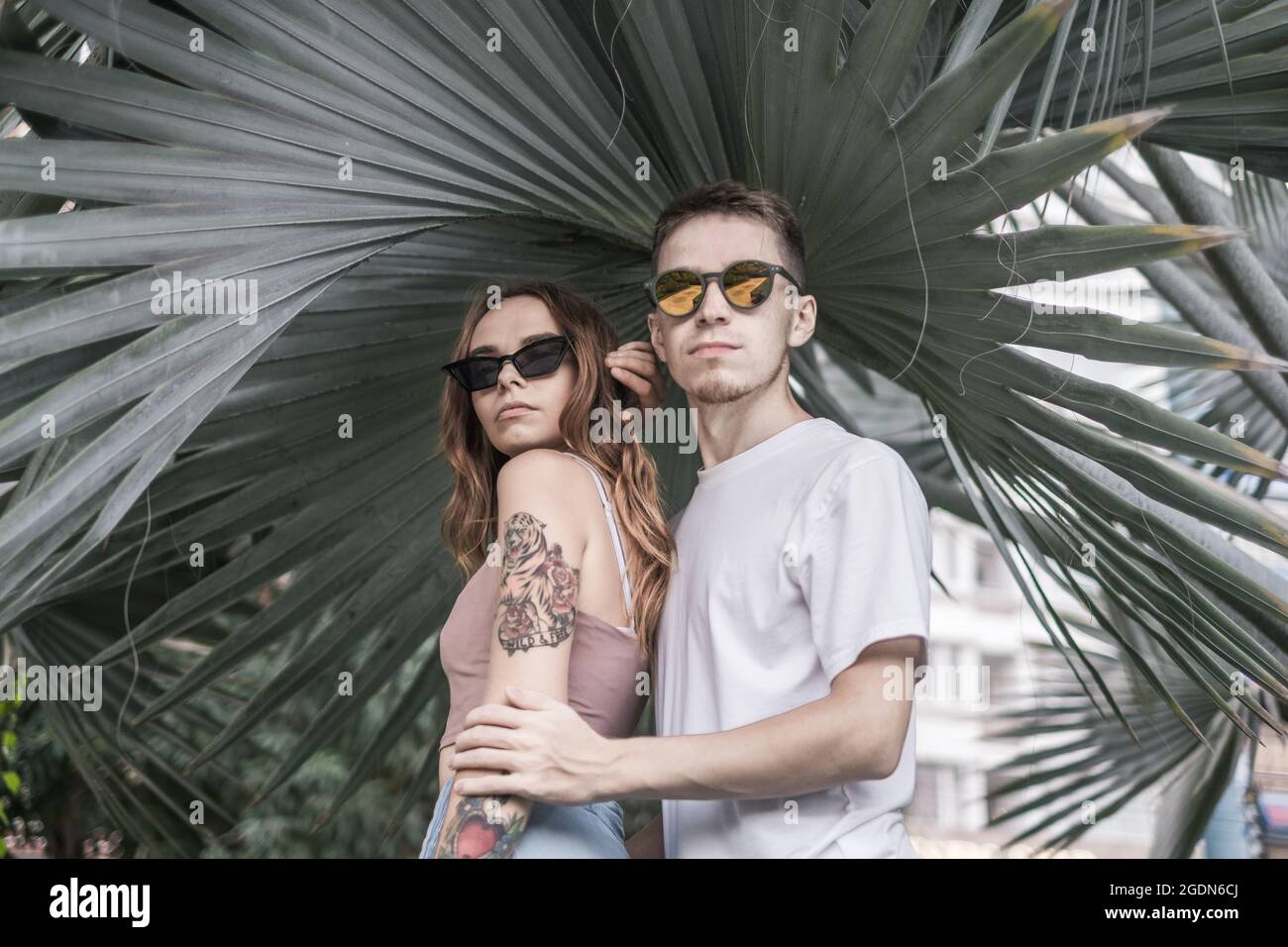 Stylish portrait of lovely couple in palm trees. Palm branches on the ...