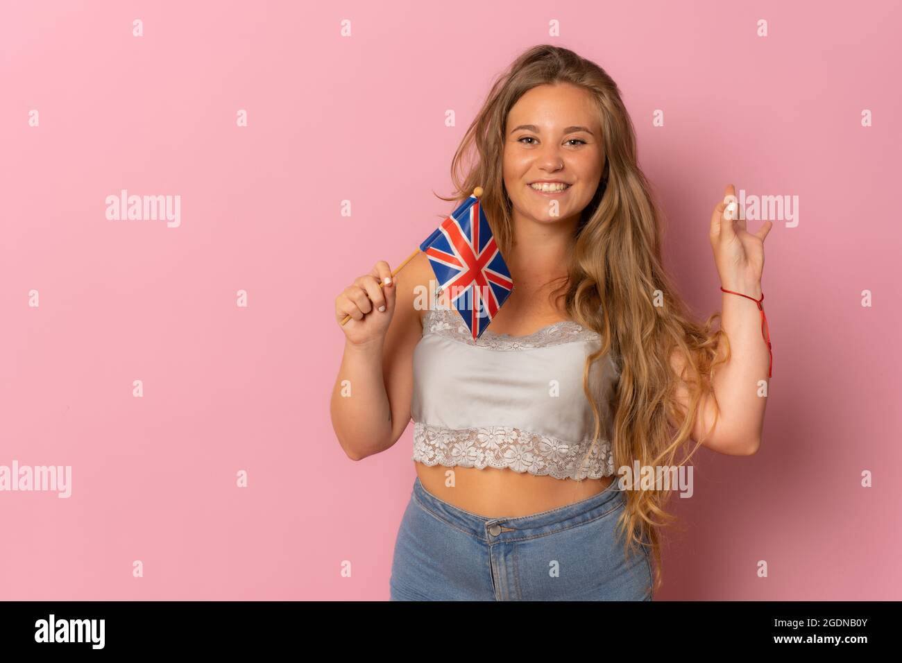 Young woman holding united kingdom flag looking positive and happy ...