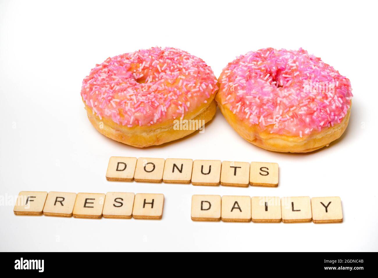 Two Iced Ring Donuts On A White Background With A Sign Reading Donuts ...