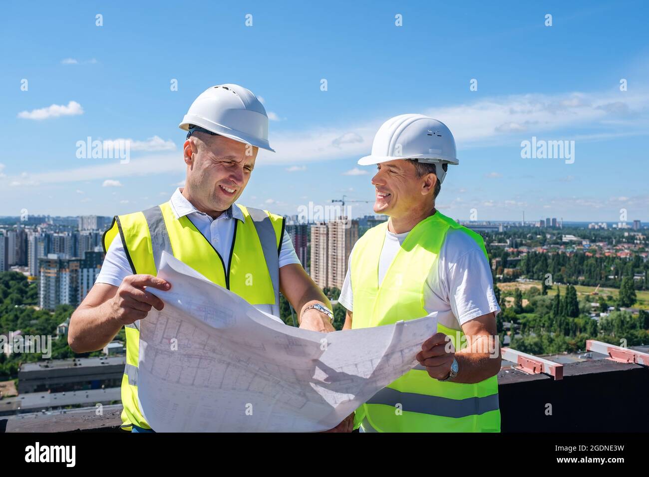 Male engineers reading blueprint together Stock Photo - Alamy