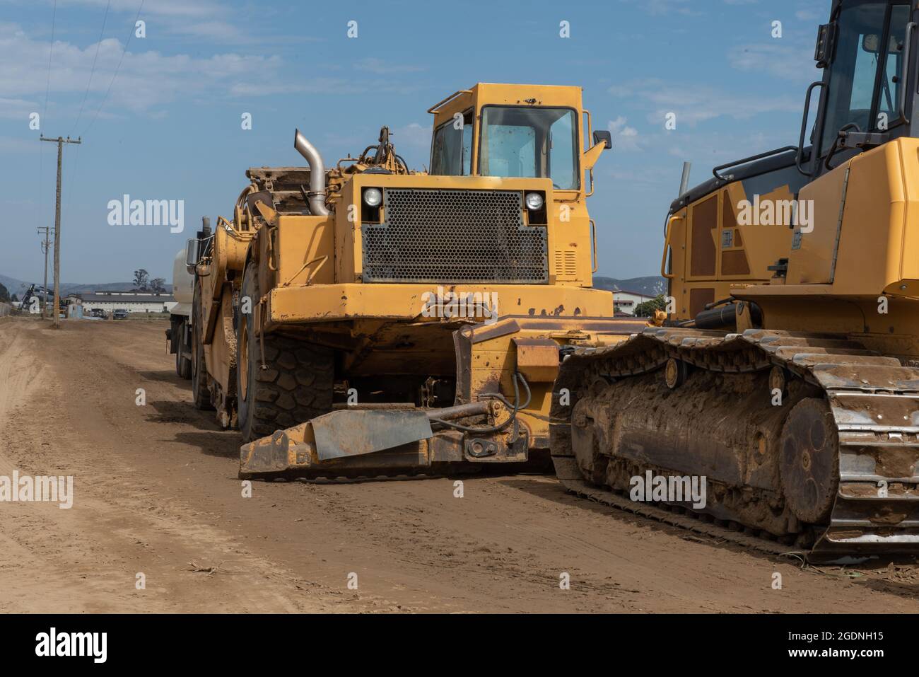 Heavy grading equipment vehicles lined up on open dirt field in ...