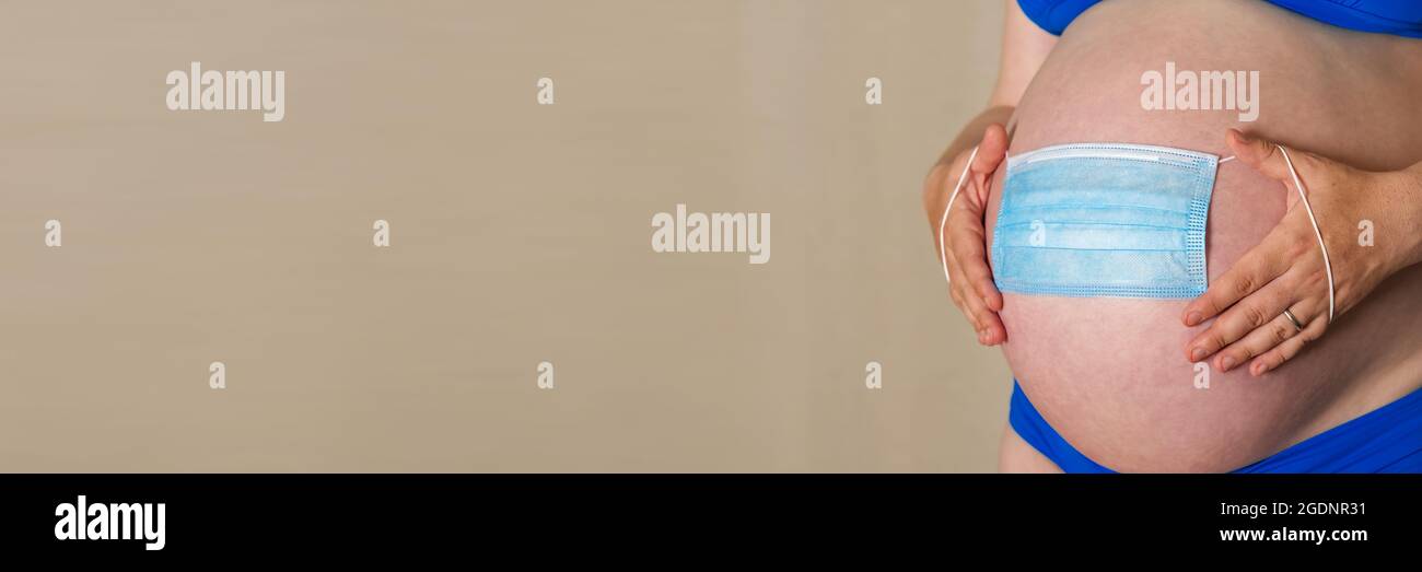 Close up of pregnant belly with surgical mask for protection concept ...